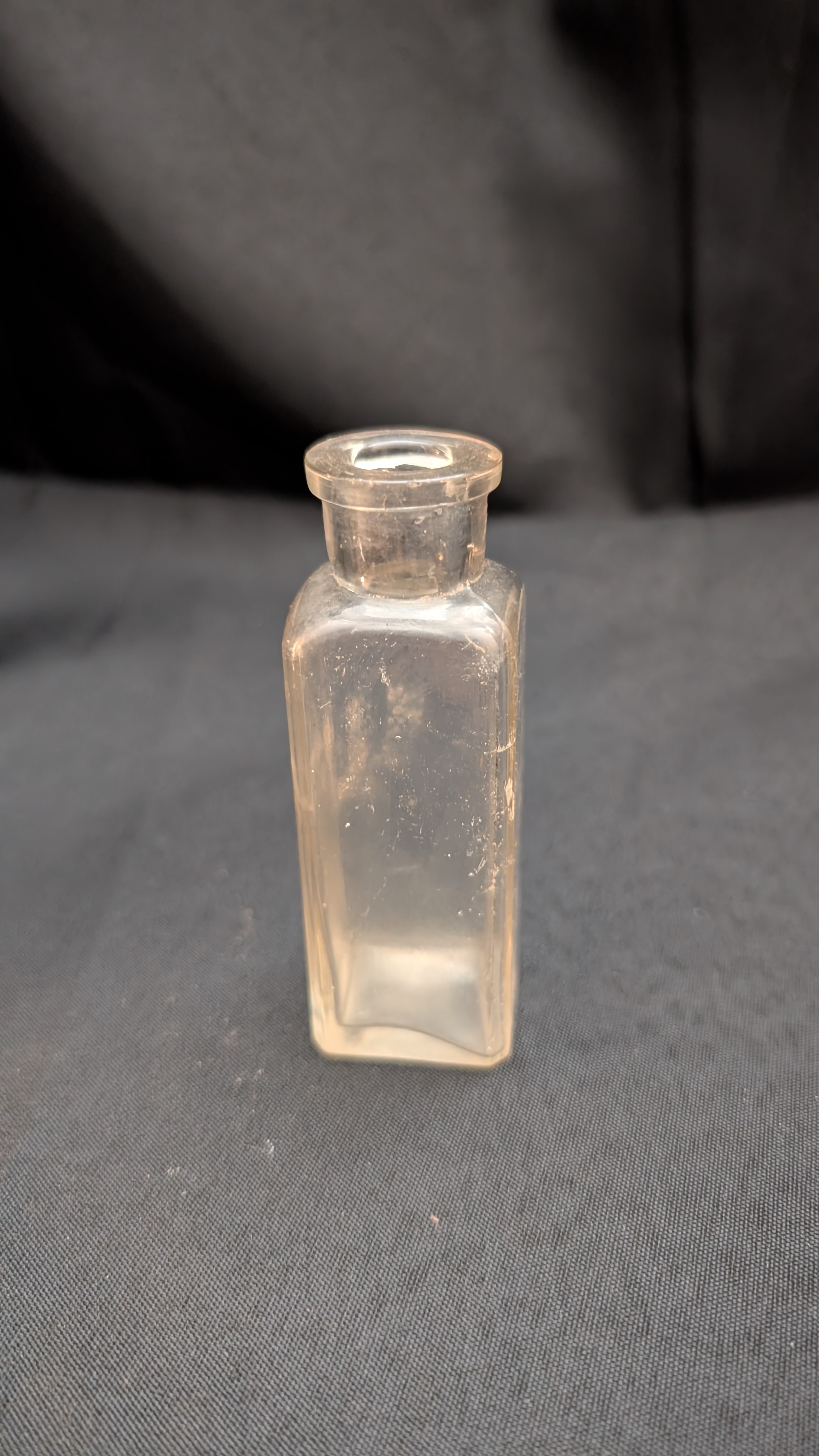 Clear small rectangular glass bottle with a smooth base. 1900-1930's