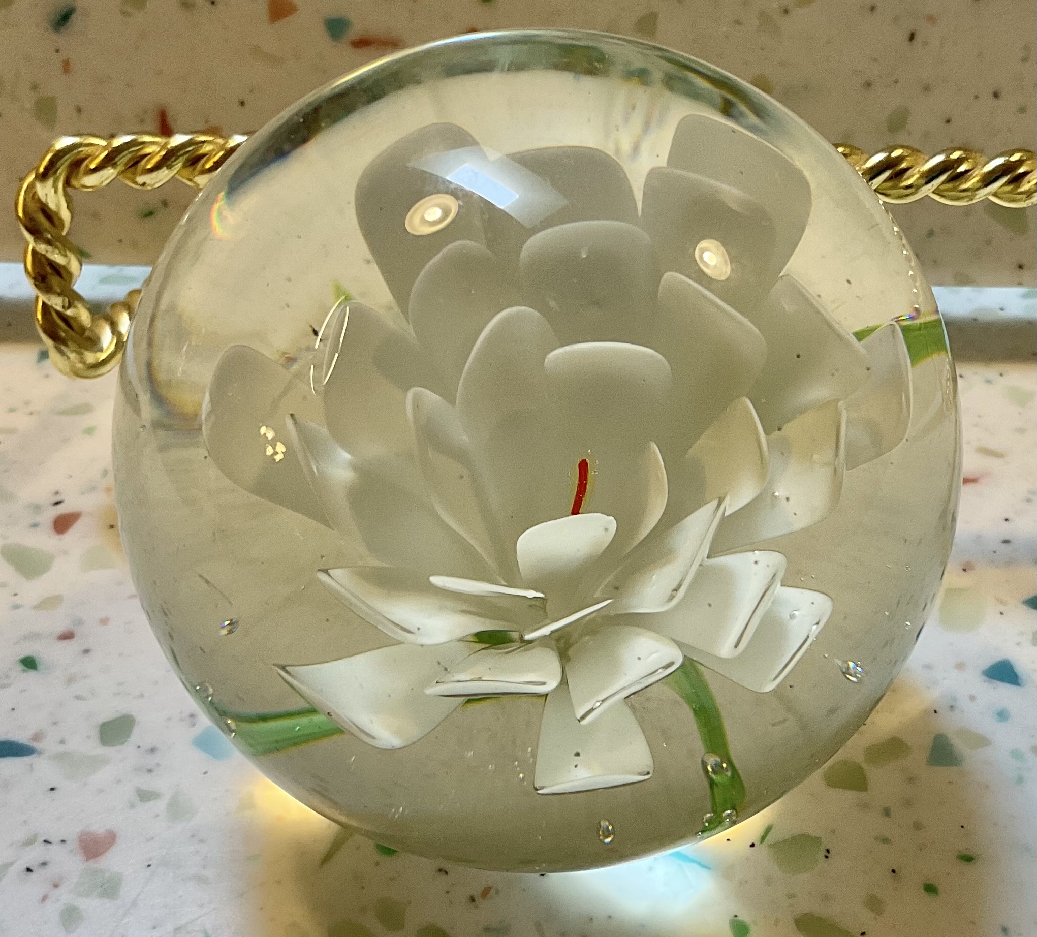 Clear glass paperweight with white flower, orange pestle, and green ...