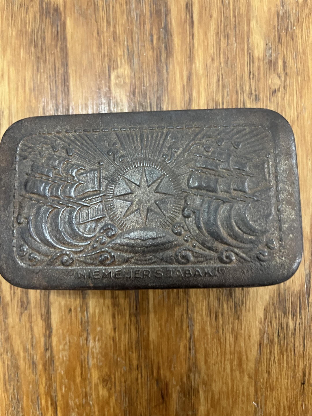 Embossed metal tobacco tin by Niemeyer featuring ships and compass.- 3x5